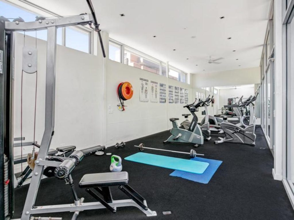 Communal gym with cardio equipment, strength machines, and a bright ...